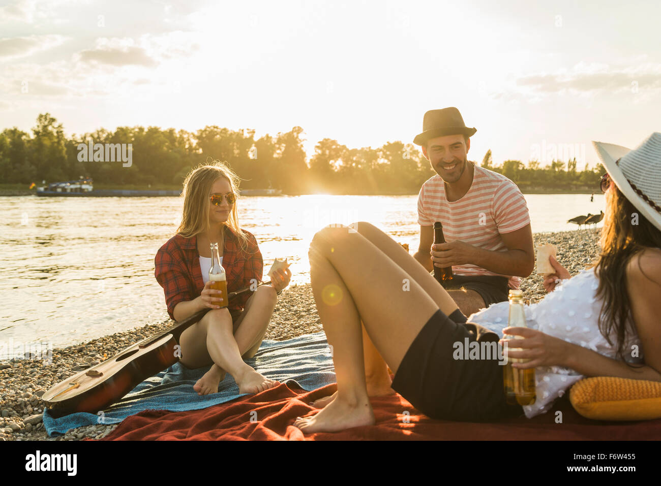 Friends relaxing at the riverside at sunset Stock Photo - Alamy