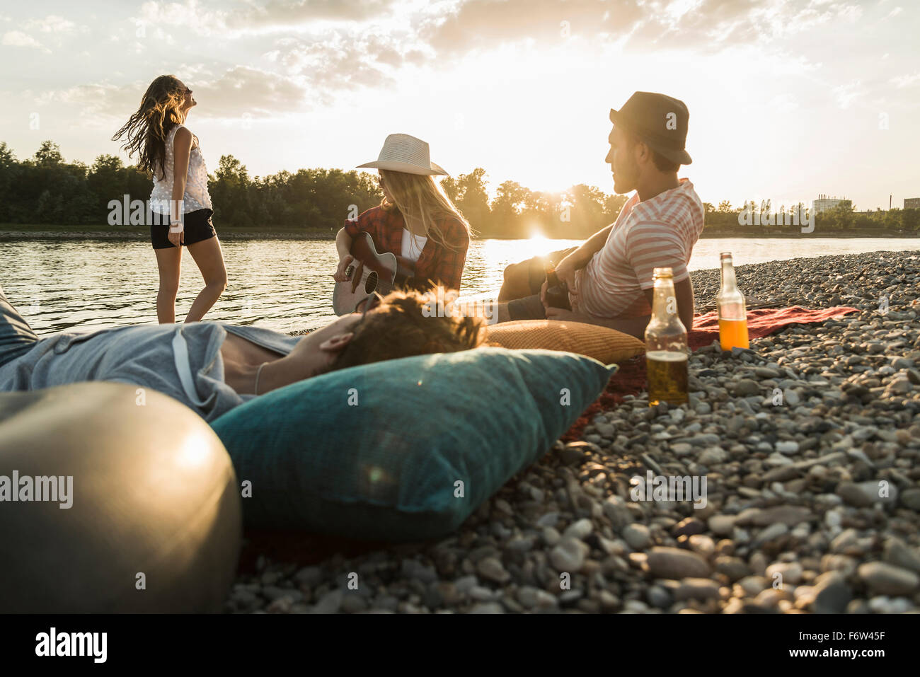 Friends relaxing at the riverside at sunset Stock Photo - Alamy