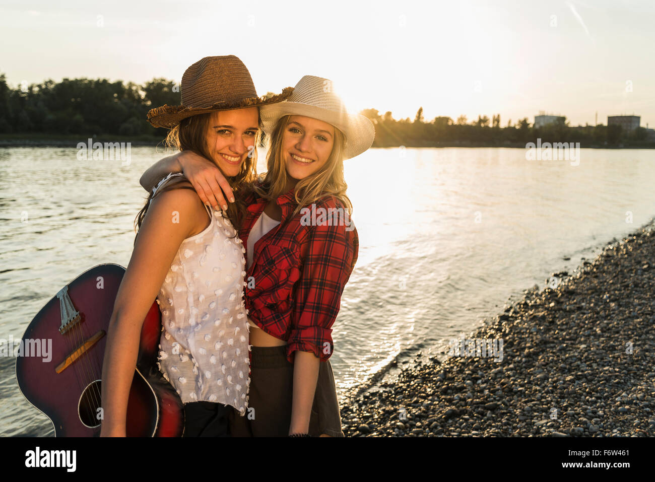 Two friends embracing at the riverside at sunset Stock Photo - Alamy