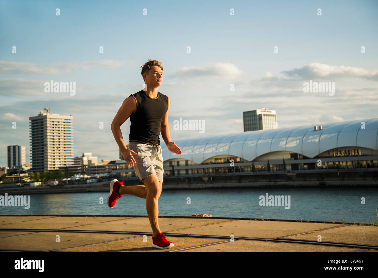 Young man running by the riverside Stock Photo - Alamy