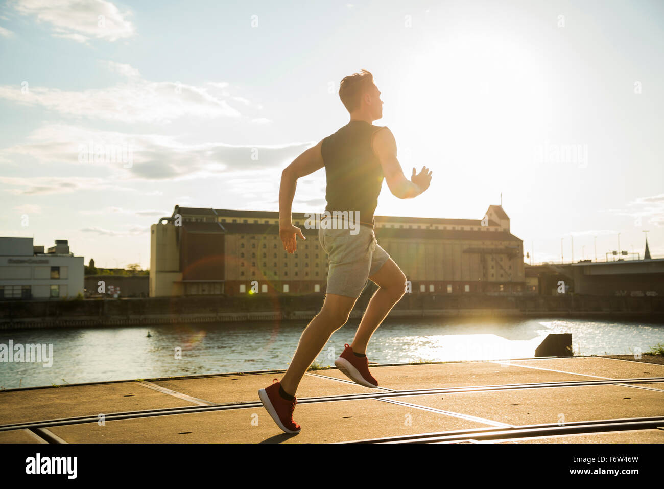 Young man running by the riverside Stock Photo - Alamy