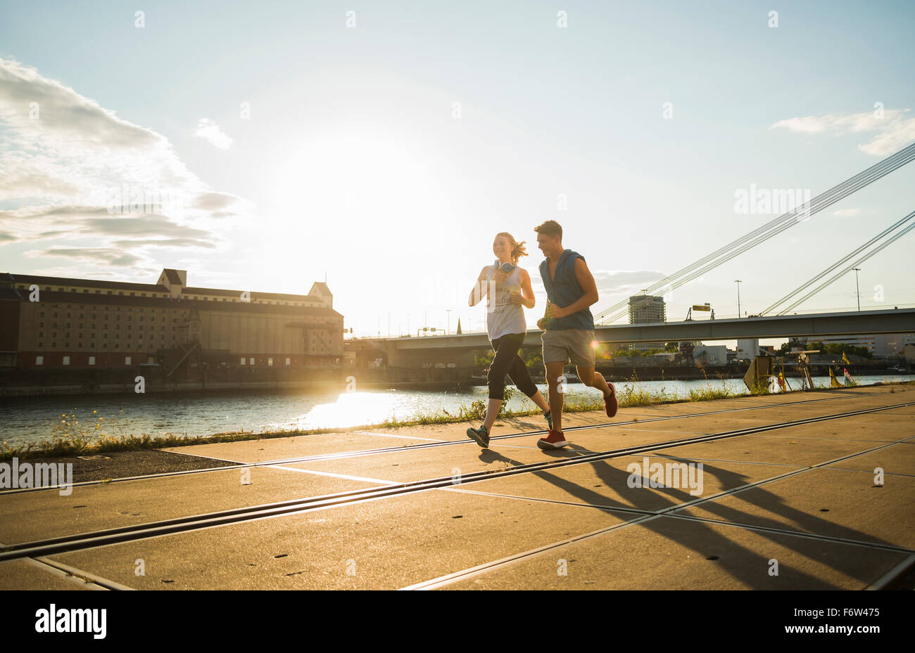 Young couple running by the riverside Stock Photo - Alamy