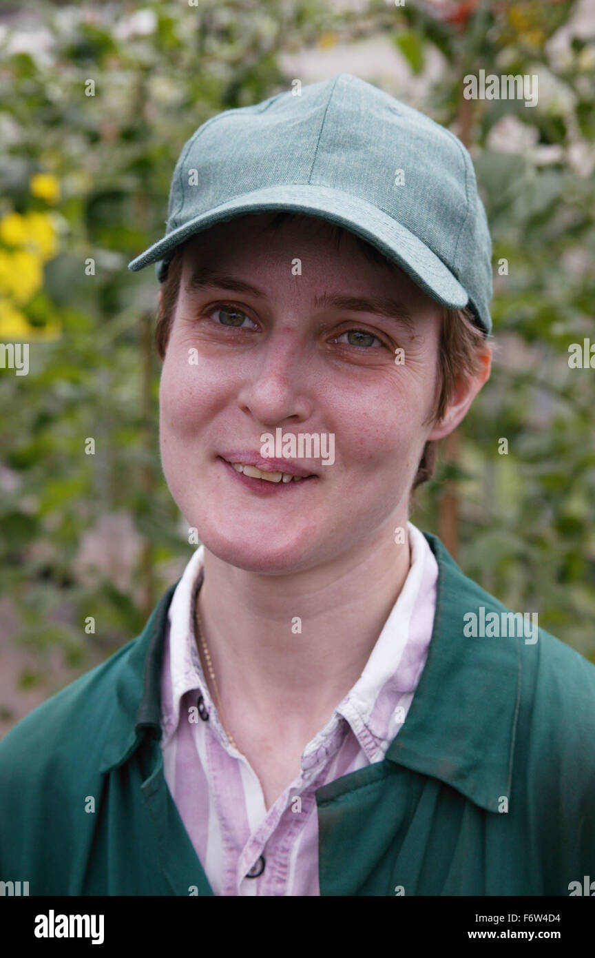 Portrait of woman with learning disability wearing overalls and cap at ...