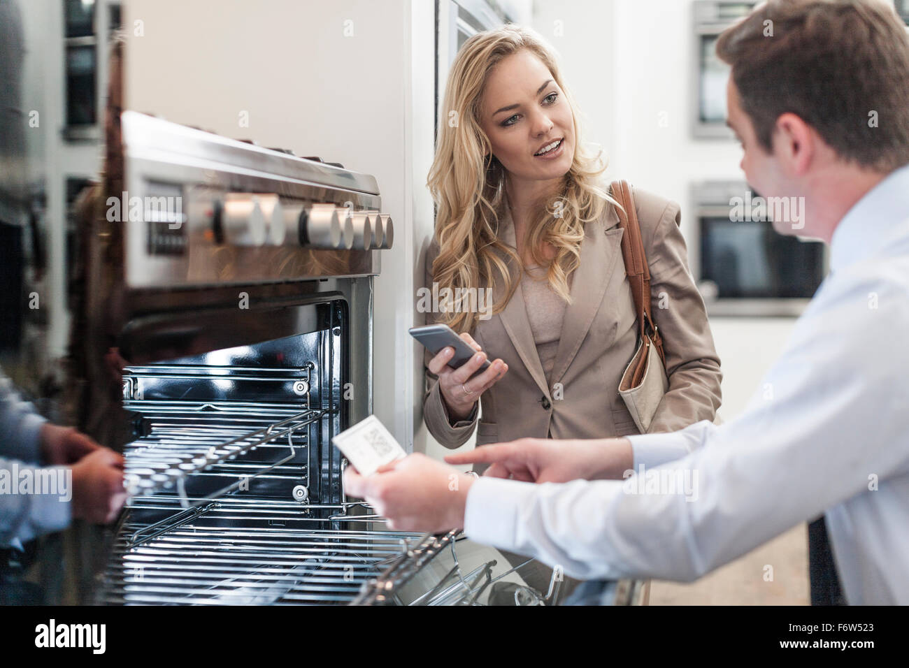 Shop assistant explaining oven to customer Stock Photo - Alamy