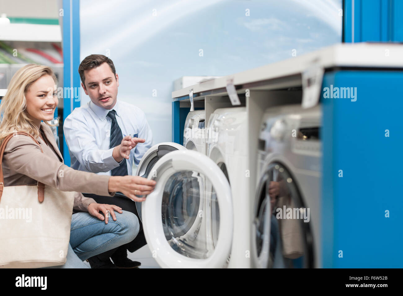 Shop assistant explaining washing machine to customer Stock Photo - Alamy
