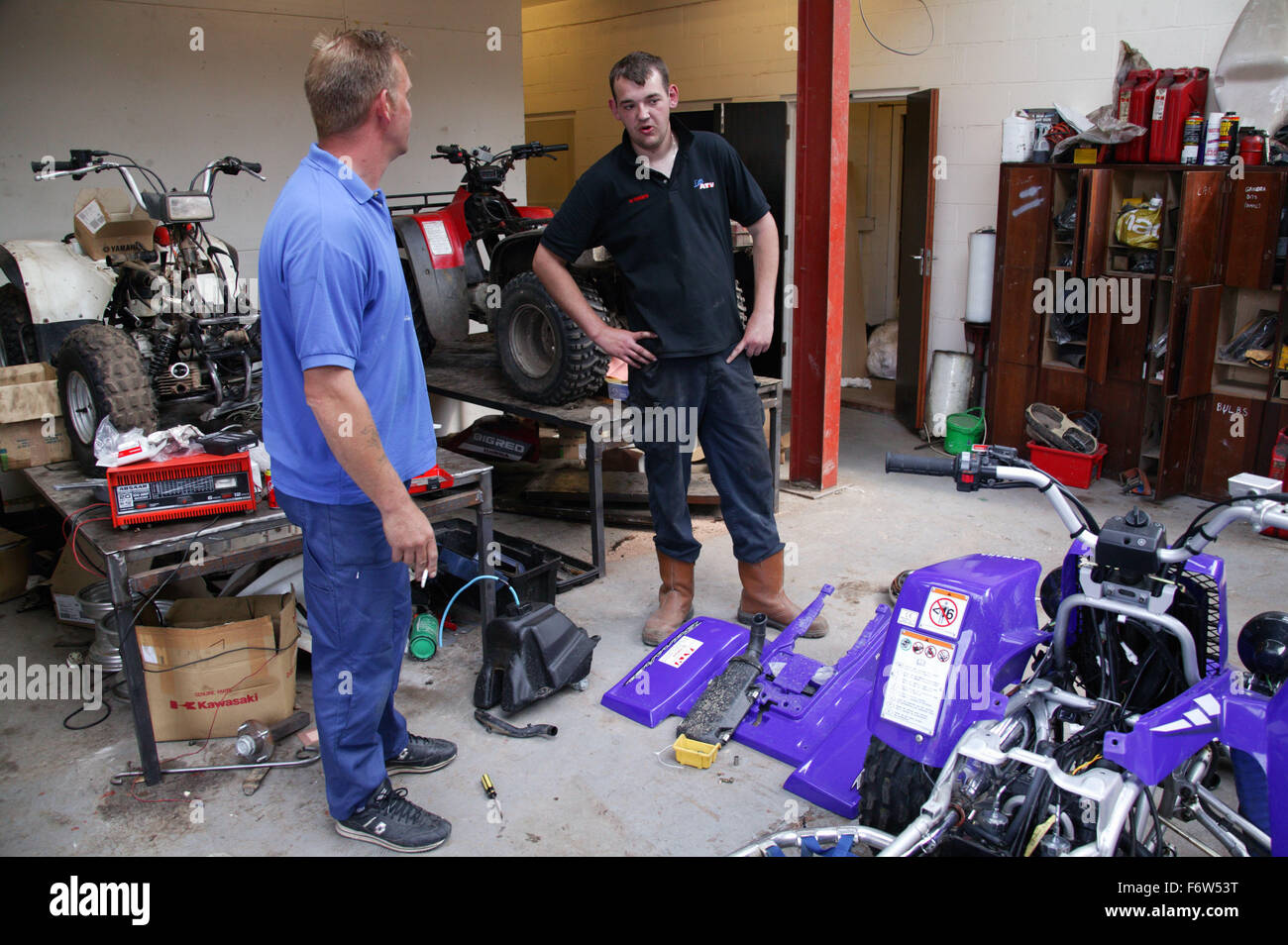 Man with Cerebral Palsy working as mechanic; talking to colleague in ...