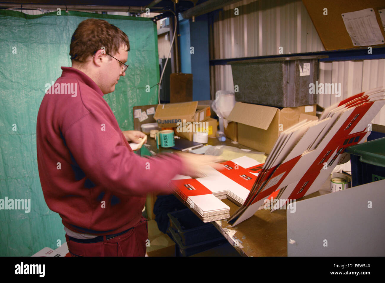 Man with learning disability working in factory assembling cardboard ...