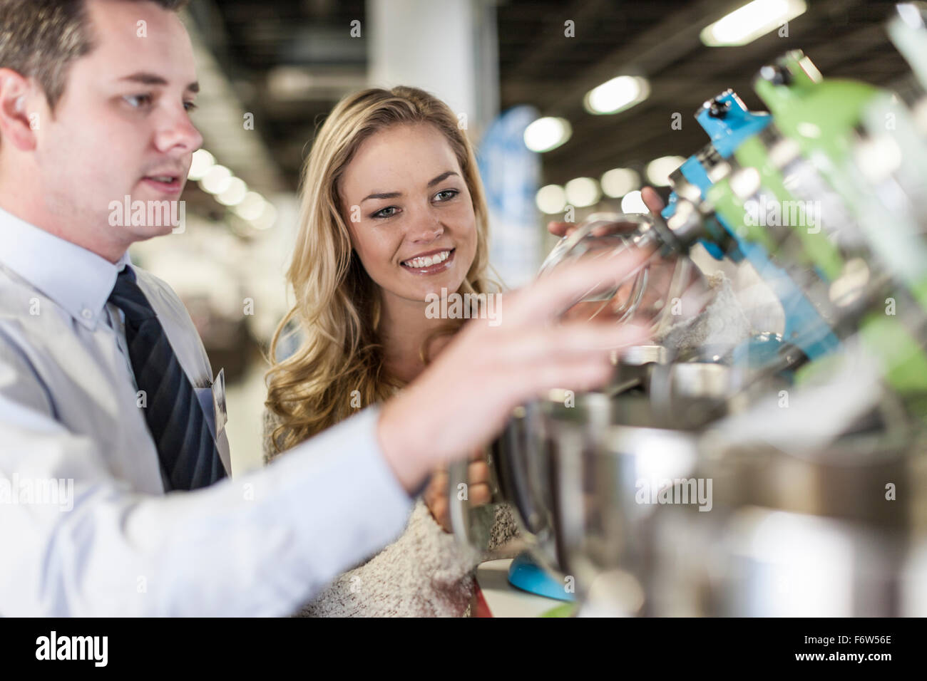 Shop assistant talking to customer shopping for kitchen utensils Stock ...