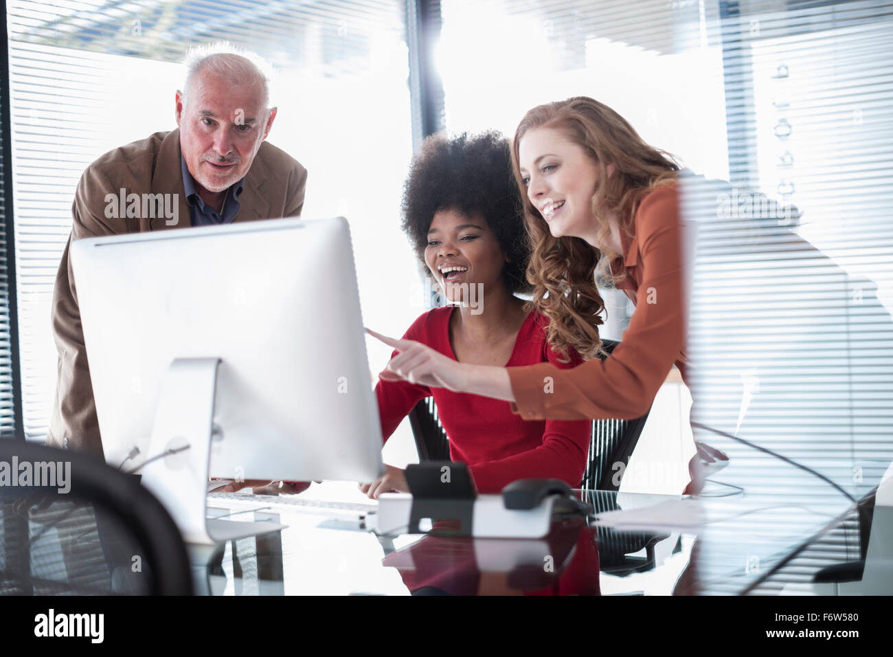 Three colleagues in office looking at computer screen Stock Photo - Alamy