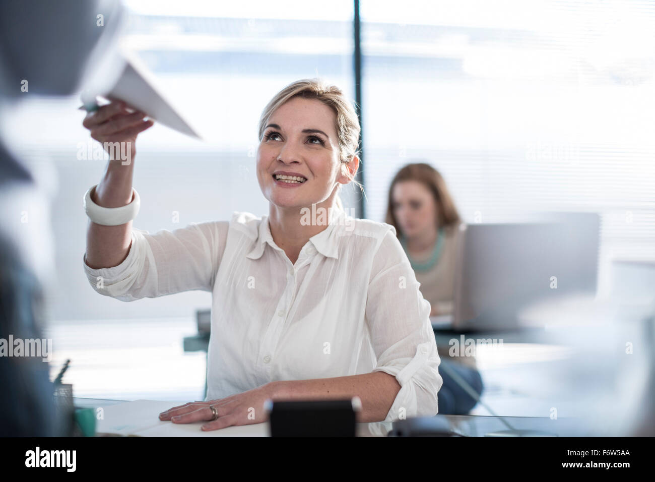 Woman in office handing over papers Stock Photo - Alamy