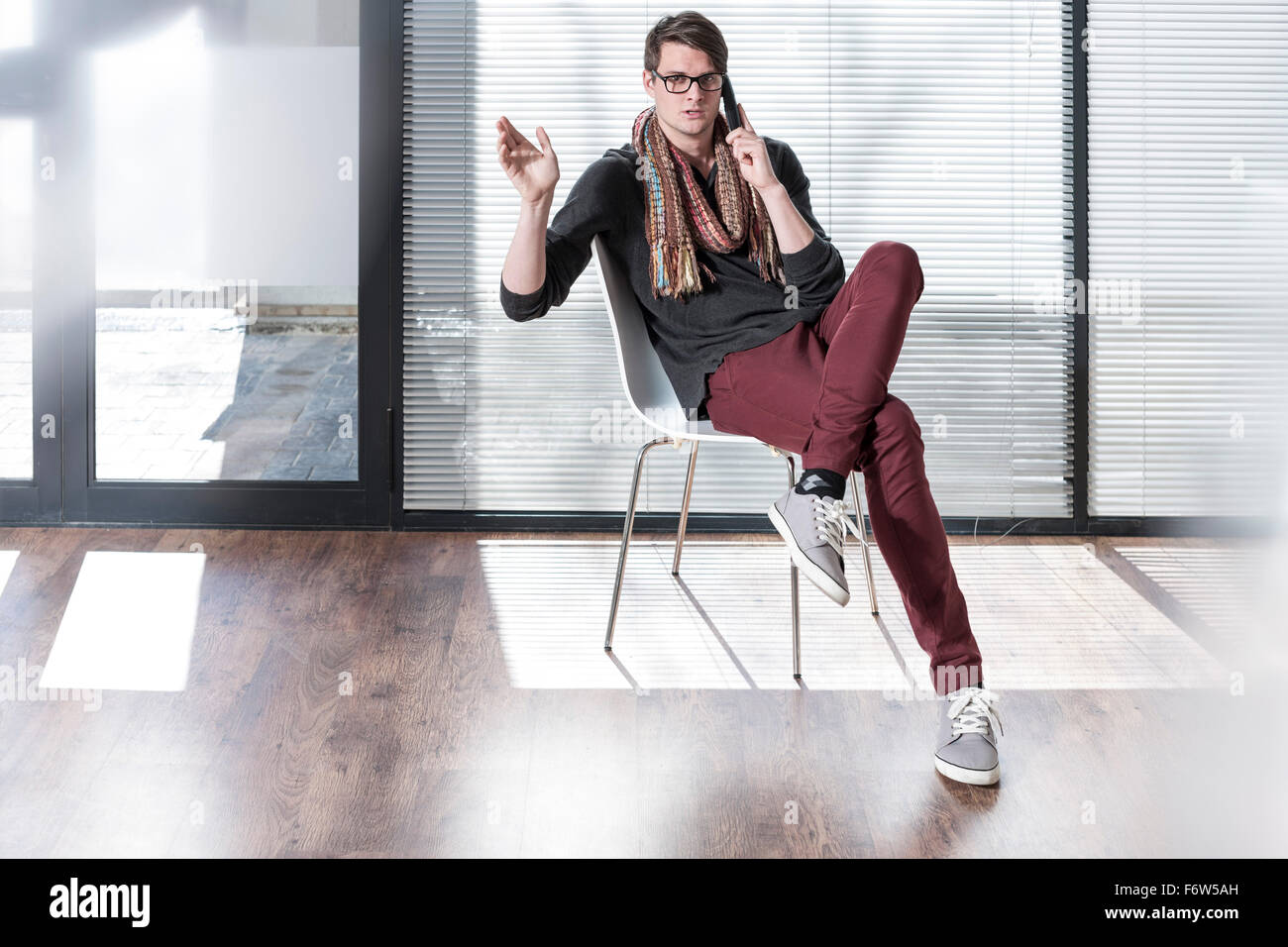 Man sitting on a chair in office telephoning Stock Photo - Alamy