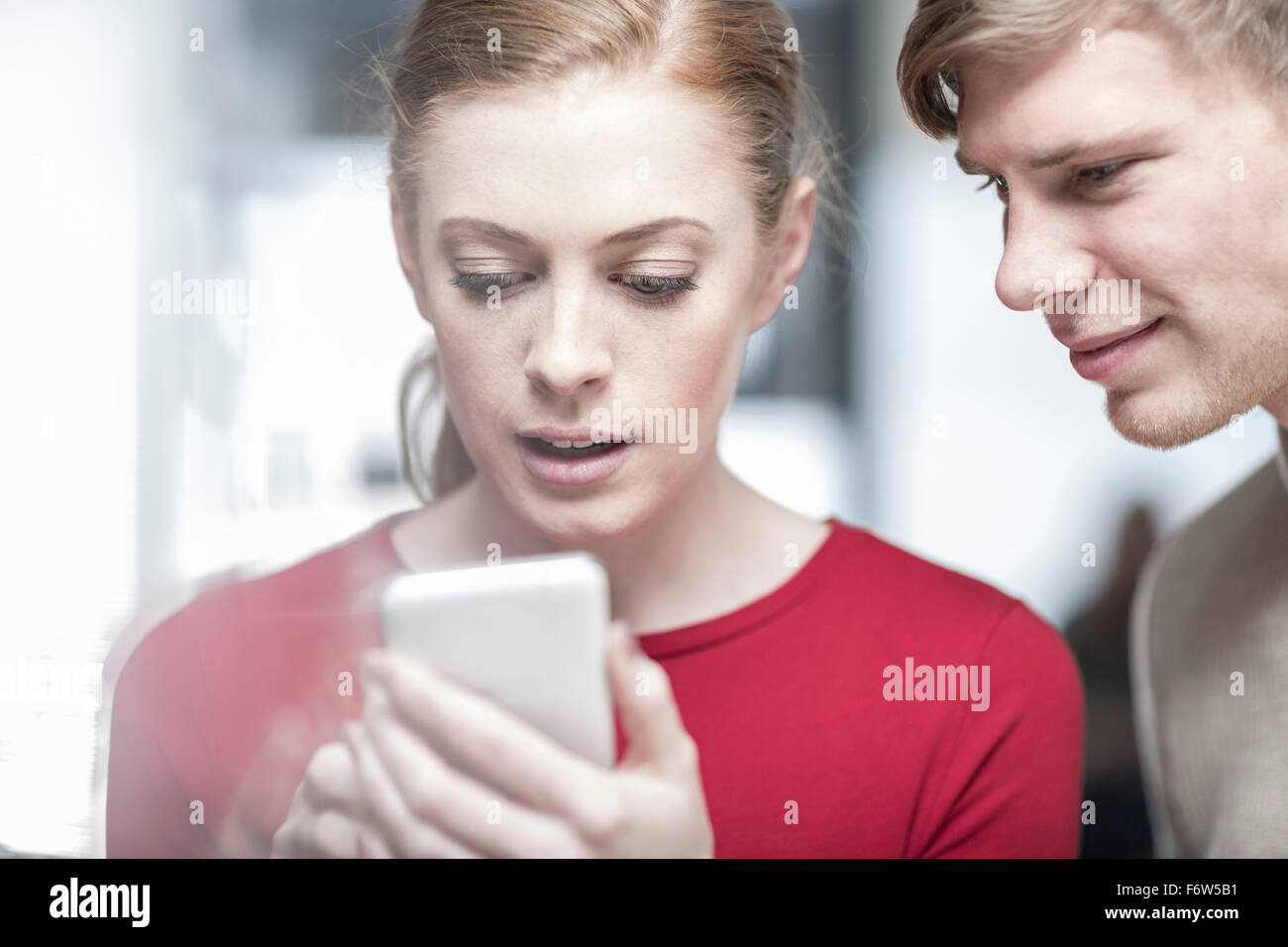 Young woman and man looking on cell phone Stock Photo - Alamy