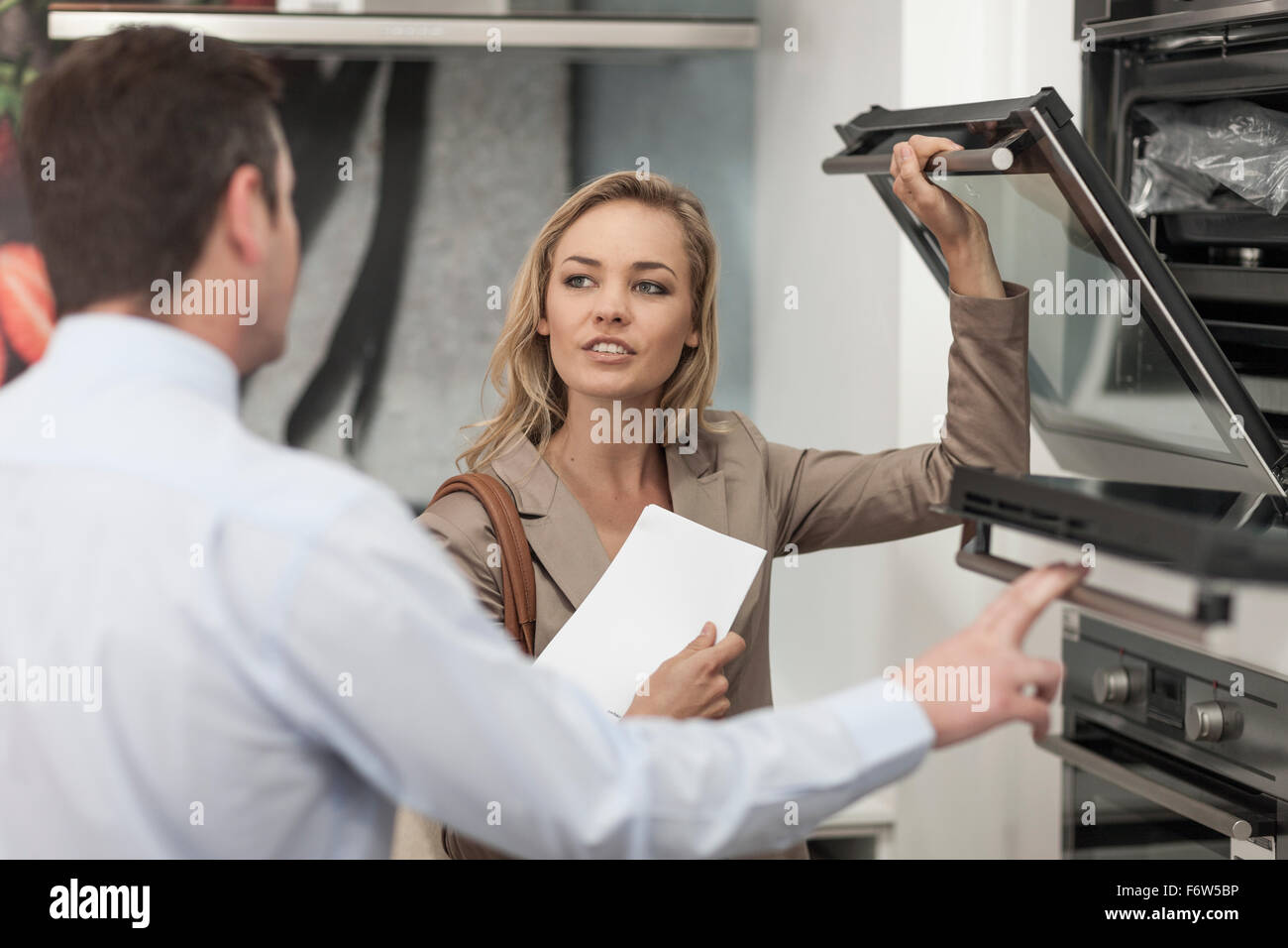 Shop assistant explaining oven to customer Stock Photo - Alamy