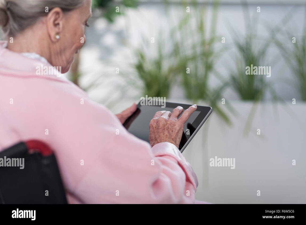 Elderly patient in wheelchair using digital tablet Stock Photo - Alamy