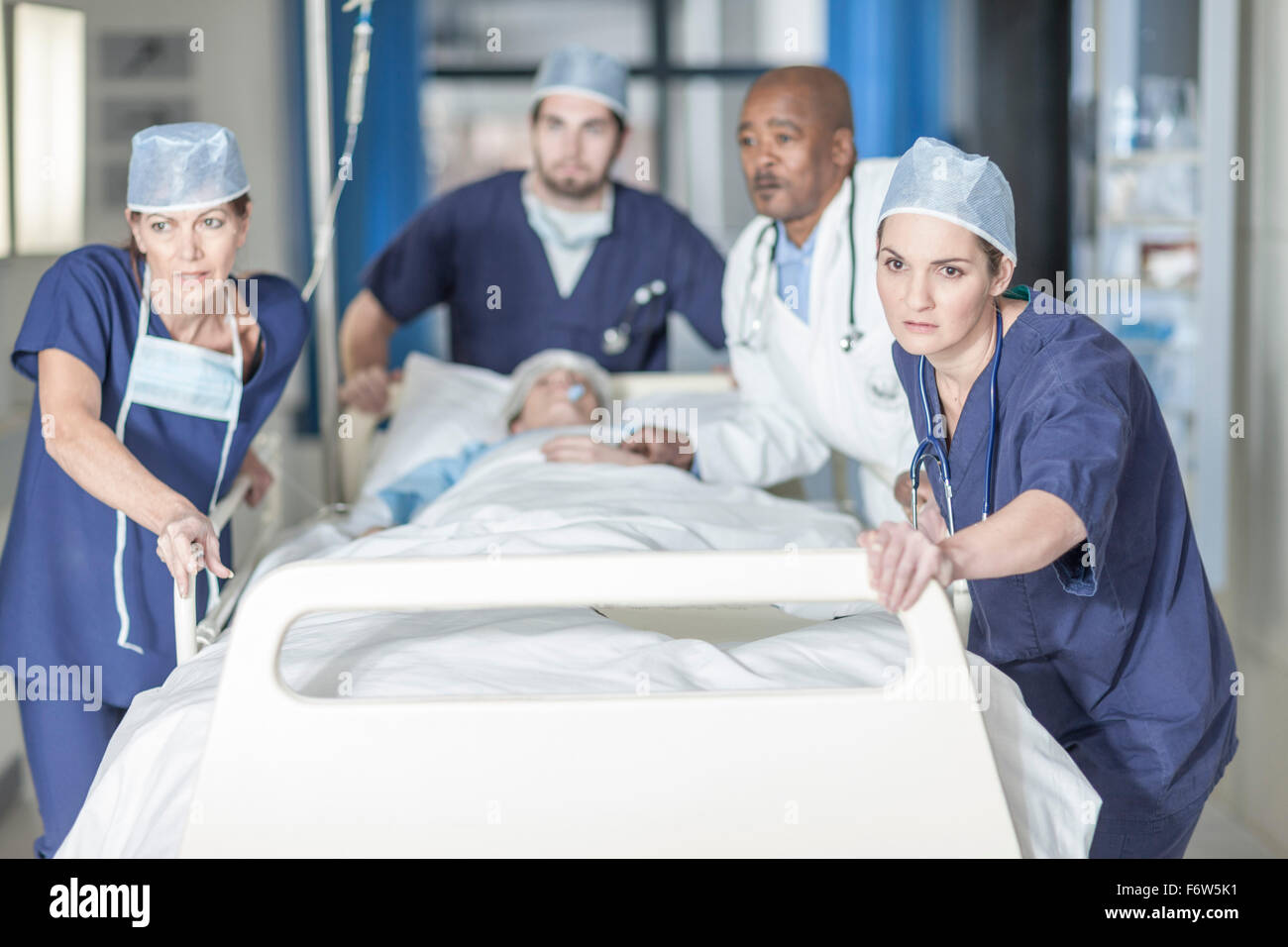 Doctors pushing a bed with patient Stock Photo - Alamy