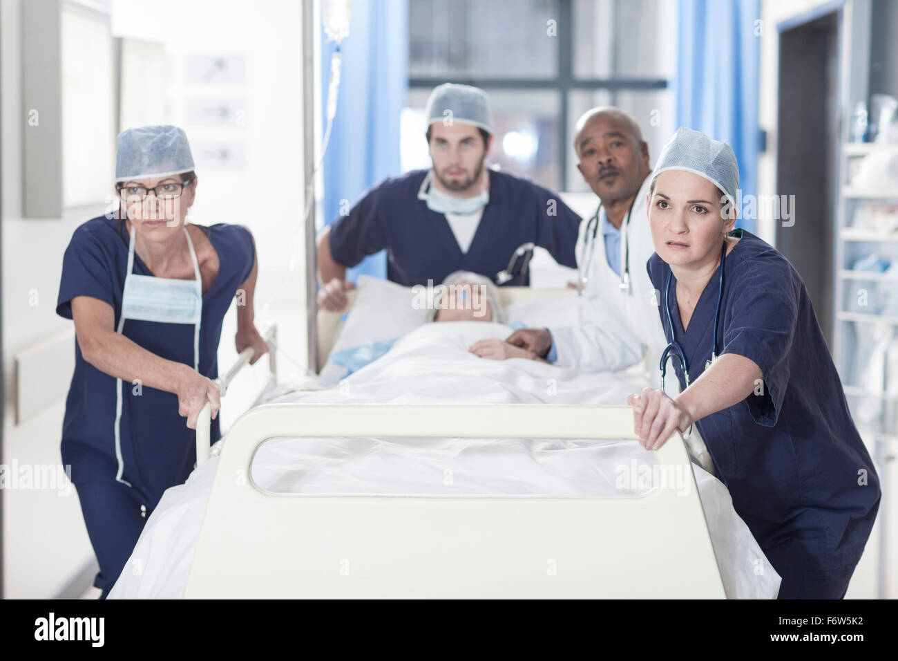 Doctors pushing a bed with patient Stock Photo - Alamy