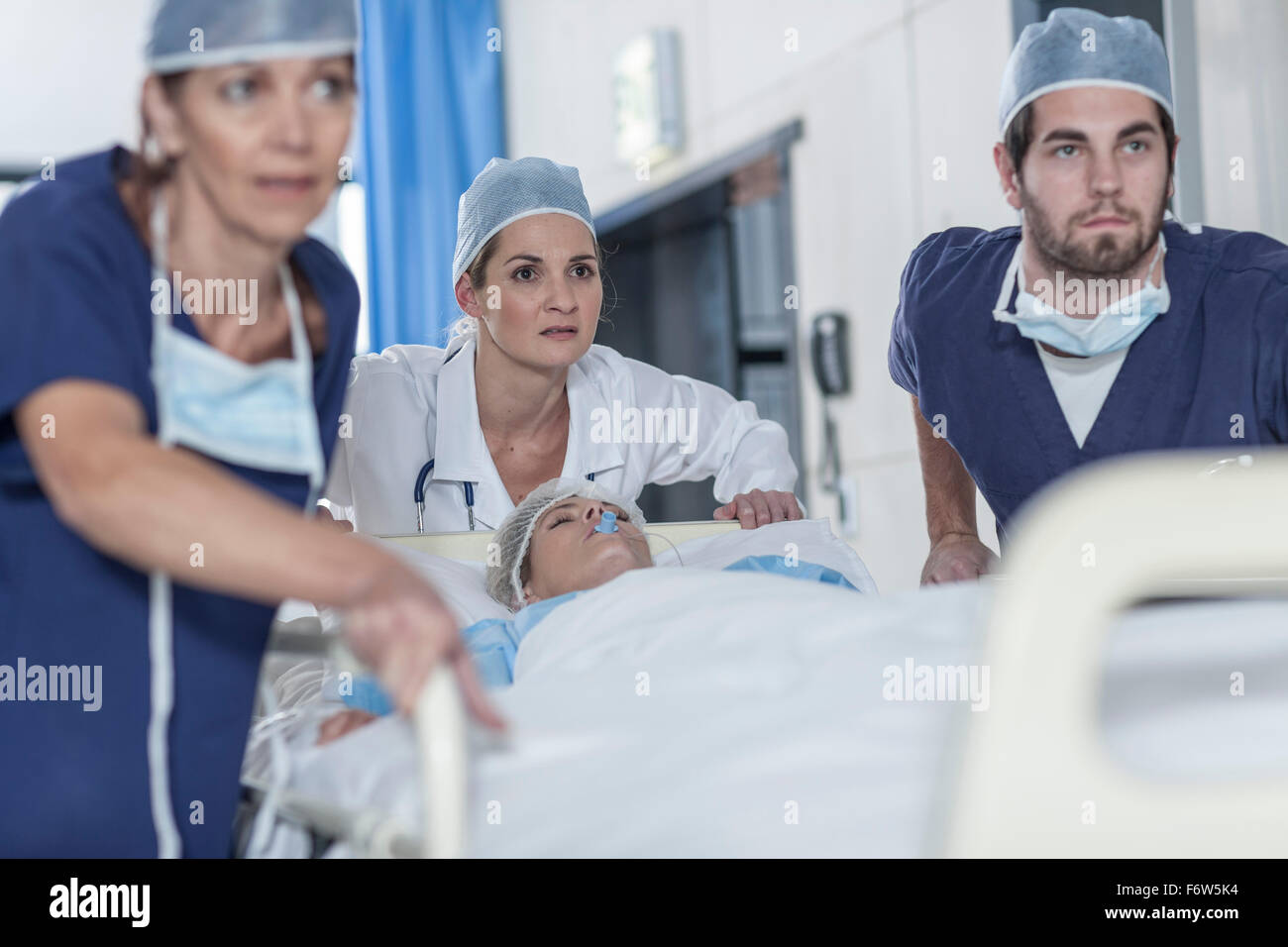 Doctors pushing a bed with patient Stock Photo - Alamy