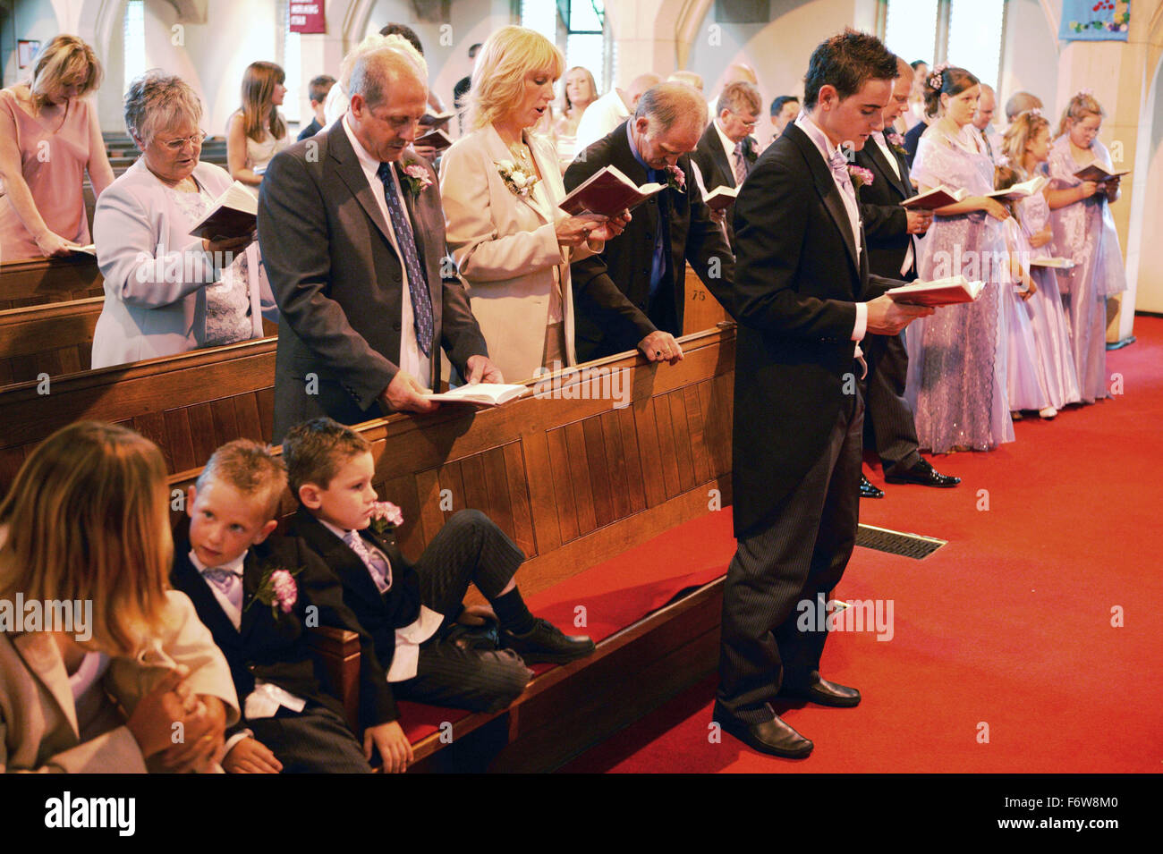 Wedding guests standing in church pews singing hymn Stock Photo - Alamy