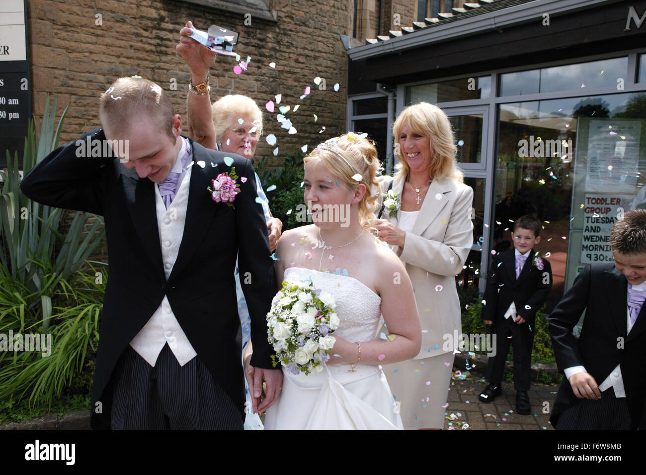 Guests throwing confetti over bride and groom outside church Stock ...
