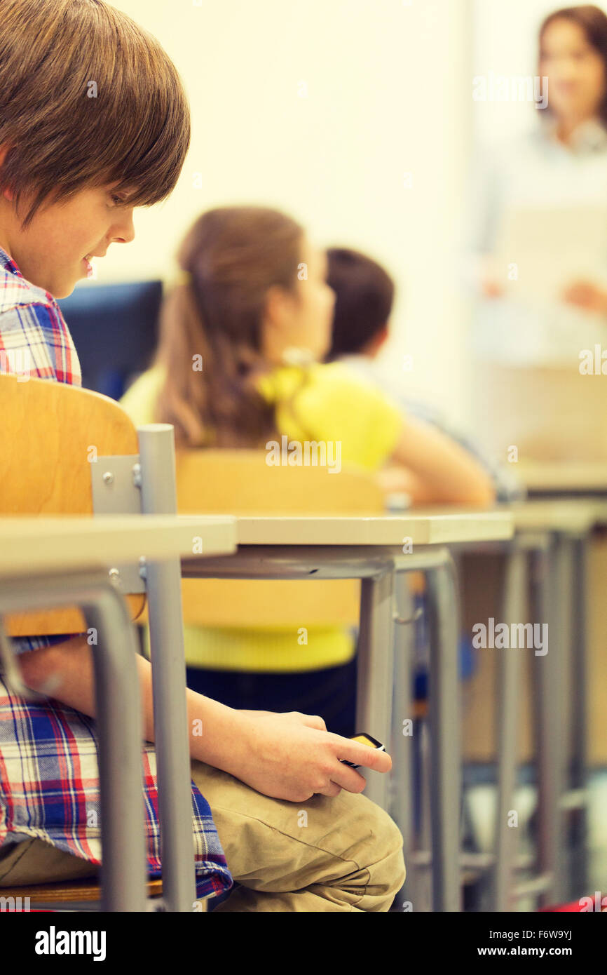 school boy with smartphone on lesson at classroom Stock Photo - Alamy