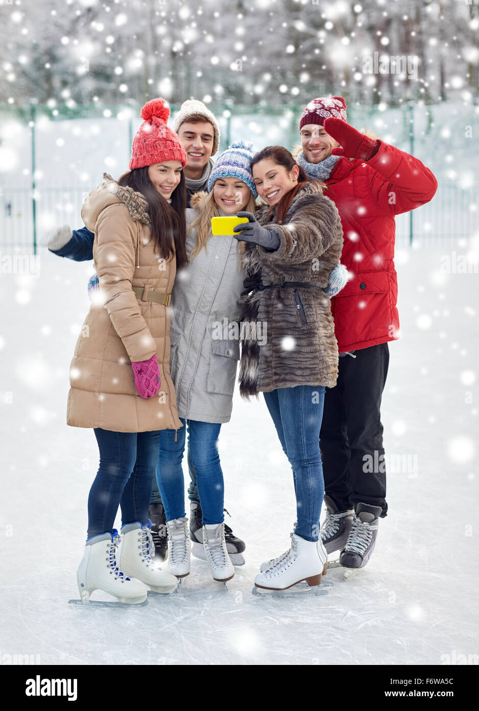 happy friends with smartphone on ice skating rink Stock Photo - Alamy