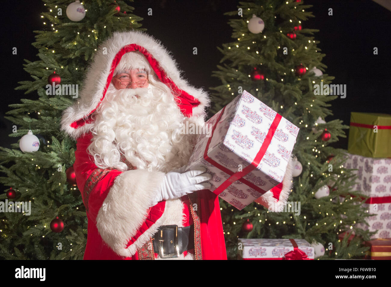 Santa Claus poses in front of a Christmas Tree and presents Stock Photo ...