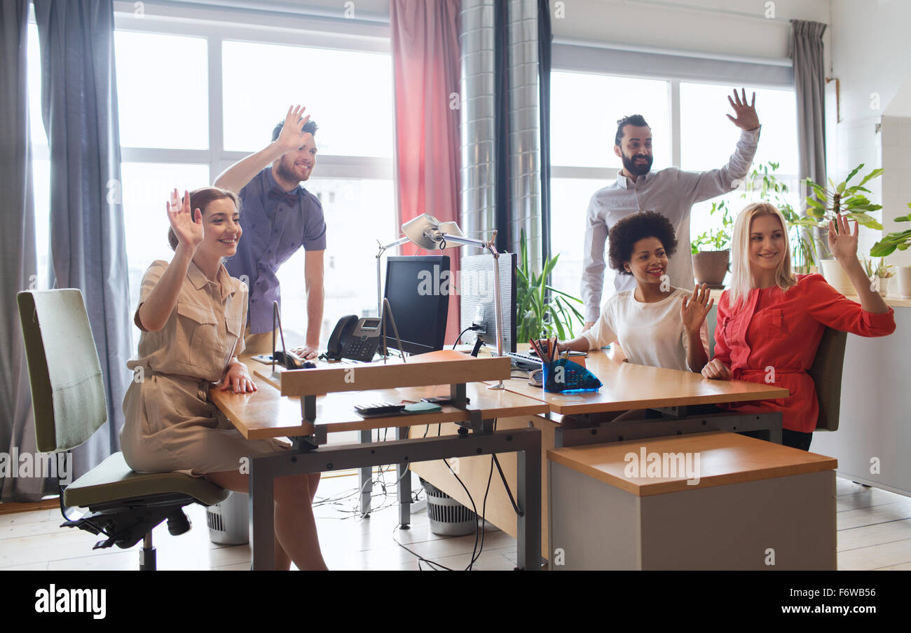 happy creative team waving hands in office Stock Photo - Alamy