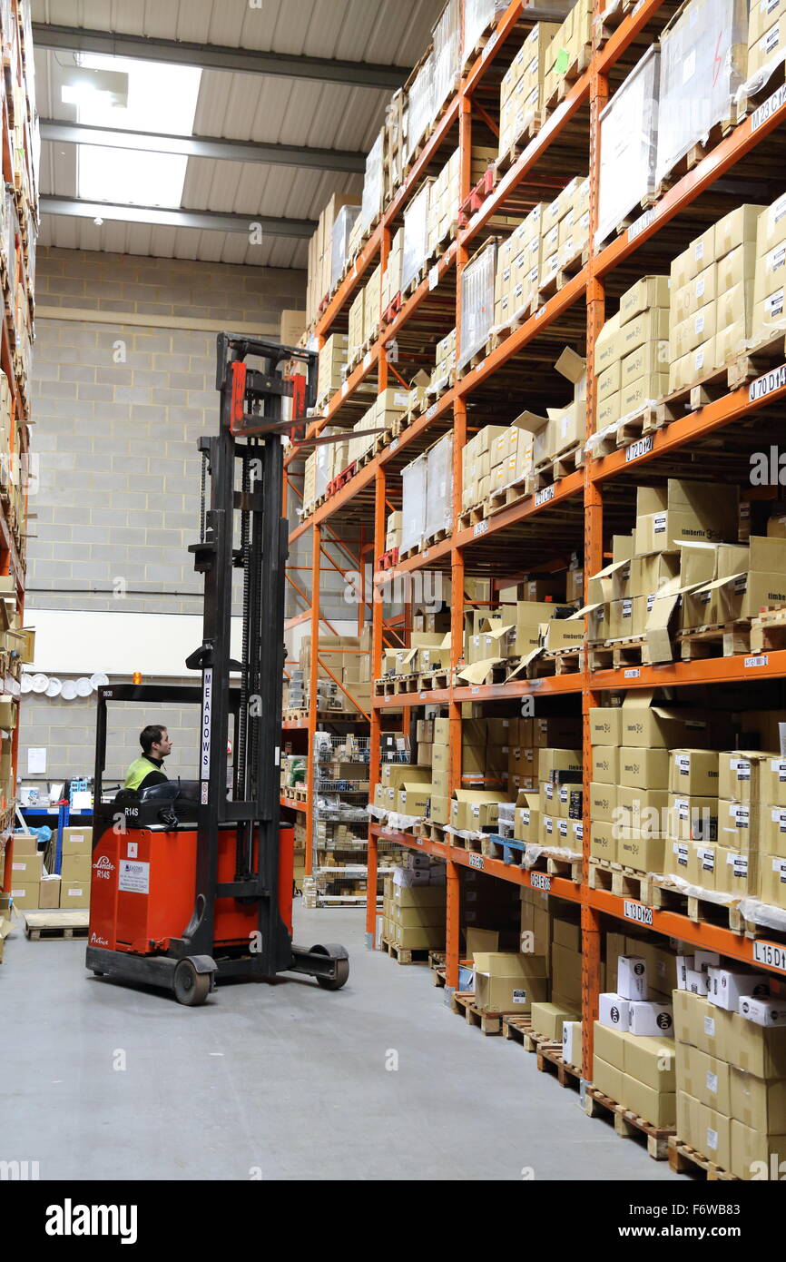 a compact, high-reach fork lift truck maneuvers in a modern storage ...