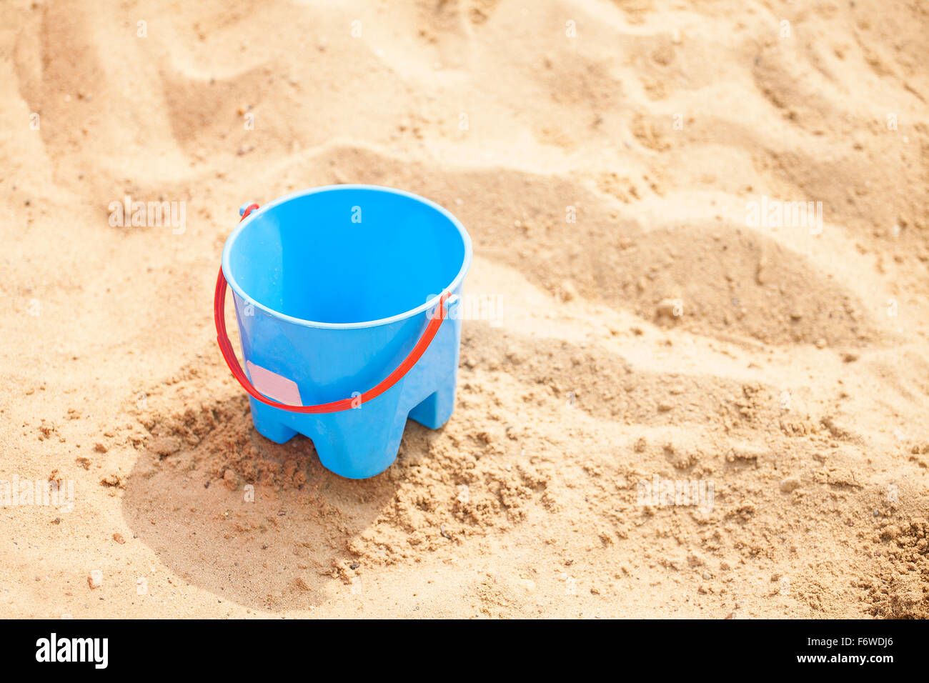 Blue empty bucket with red handle on sand background Stock Photo - Alamy