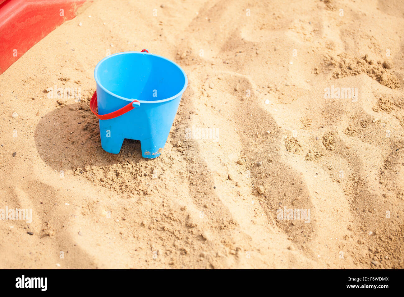 Blue empty bucket with red handle on sand background Stock Photo - Alamy