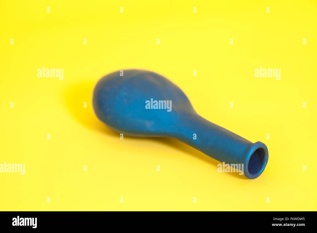 Blue deflated balloon on yellow background Stock Photo - Alamy
