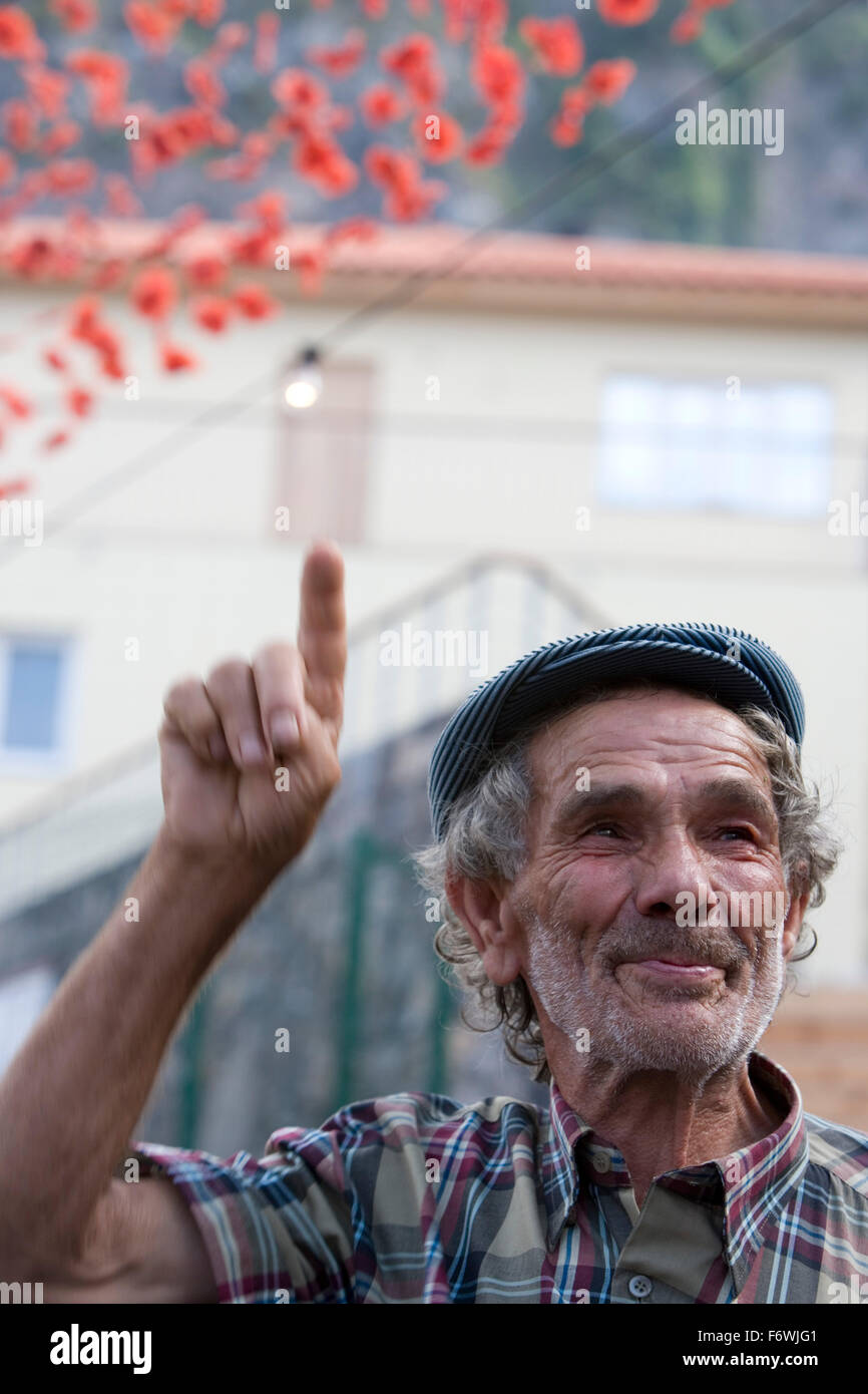 Cheerful elderly man raising his finger at a festival honoring the ...