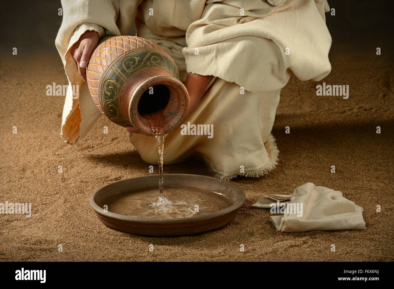 Jesus pouring water from jar into pan over dark background Stock Photo ...