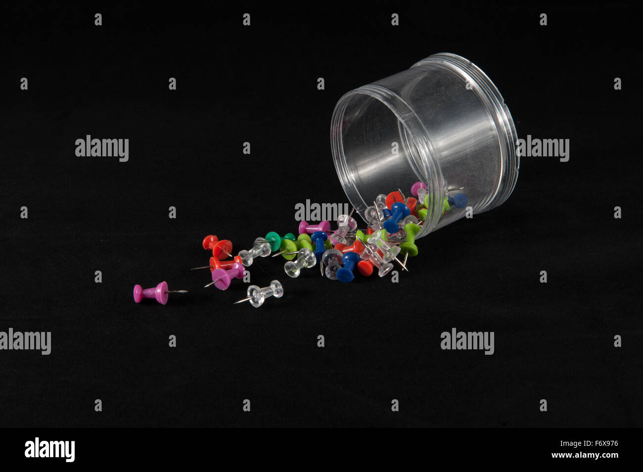 Fallen container of push pins against a black background Stock Photo ...