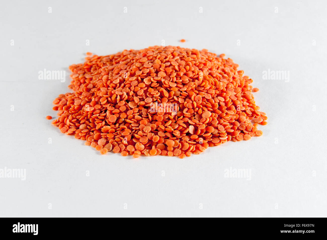 Split red lentils against a white background Stock Photo - Alamy