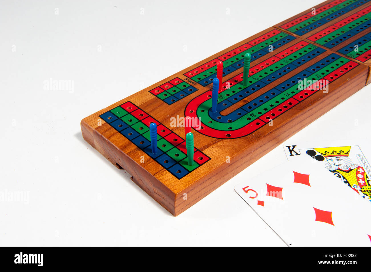 Cribbage board with red, green and blue pegs against a white background ...