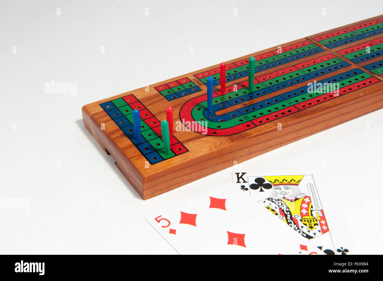 Cribbage board with red, green and blue pegs against a white background ...
