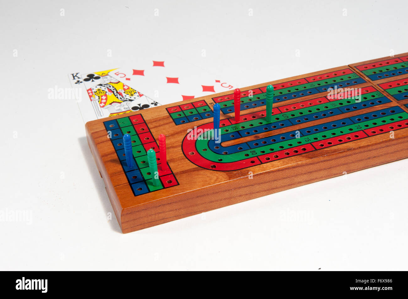 Cribbage board with red, green and blue pegs against a white background ...