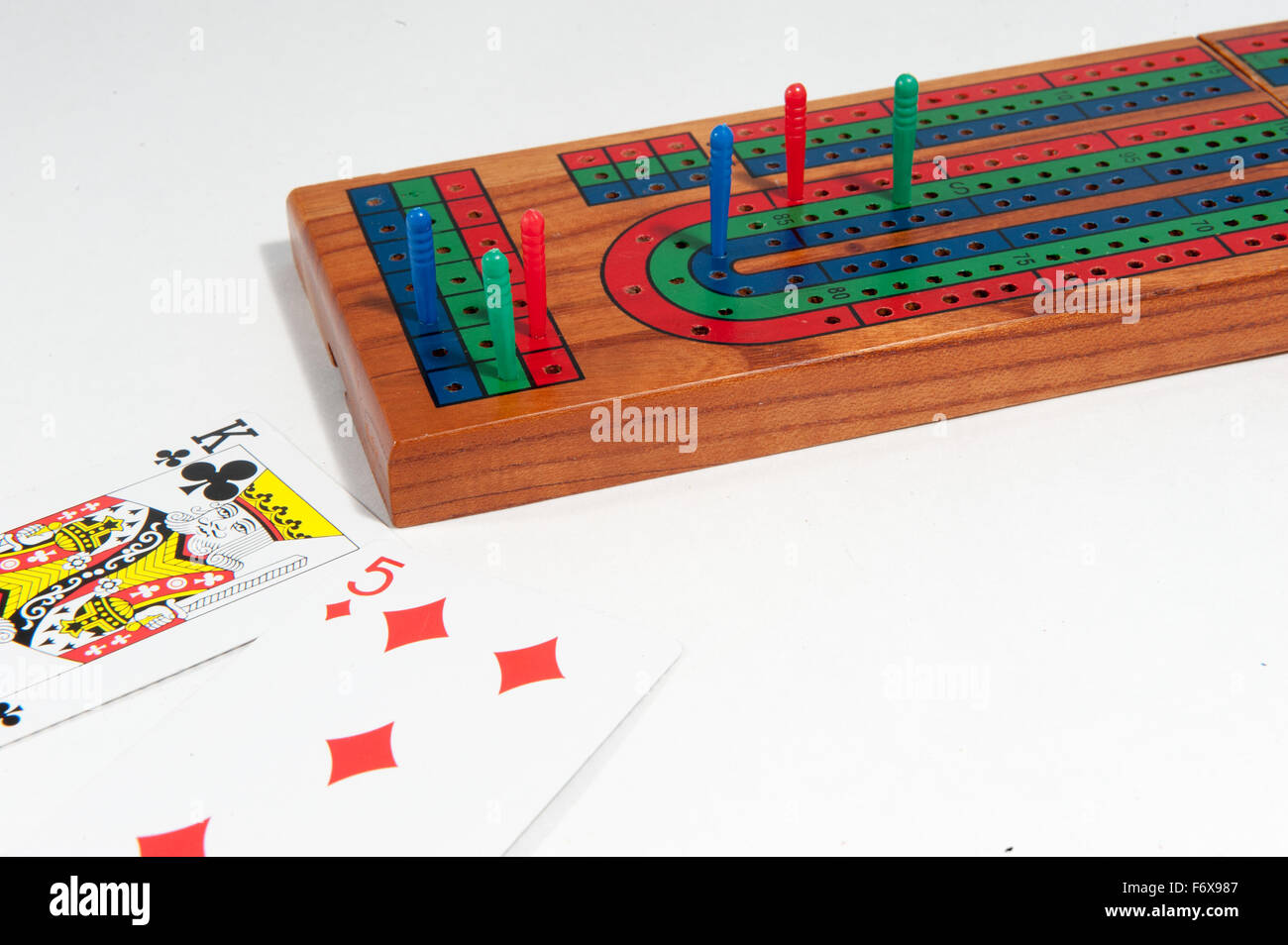 Cribbage board with red, green and blue pegs against a white background ...