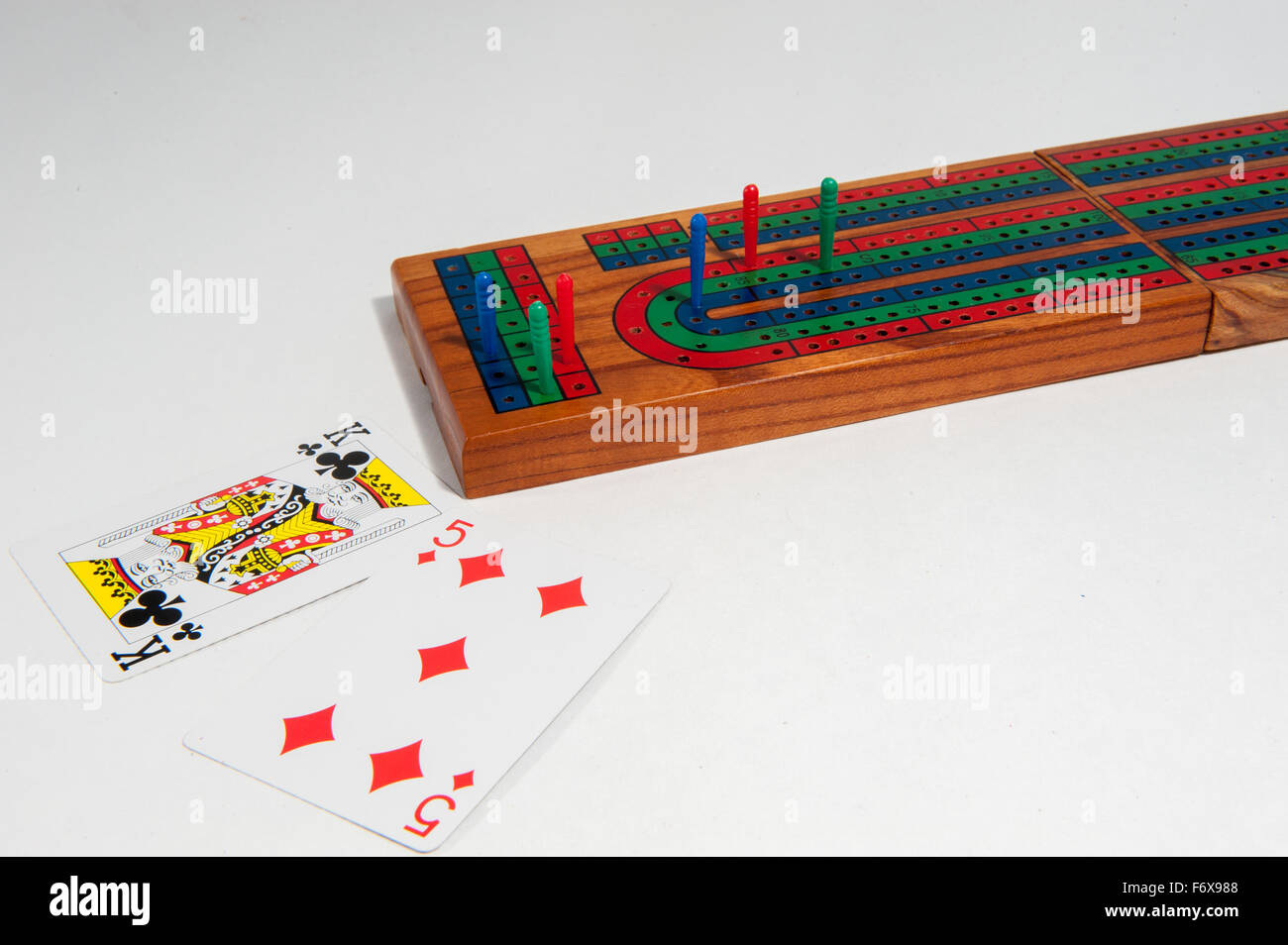 Cribbage board with red, green and blue pegs against a white background ...