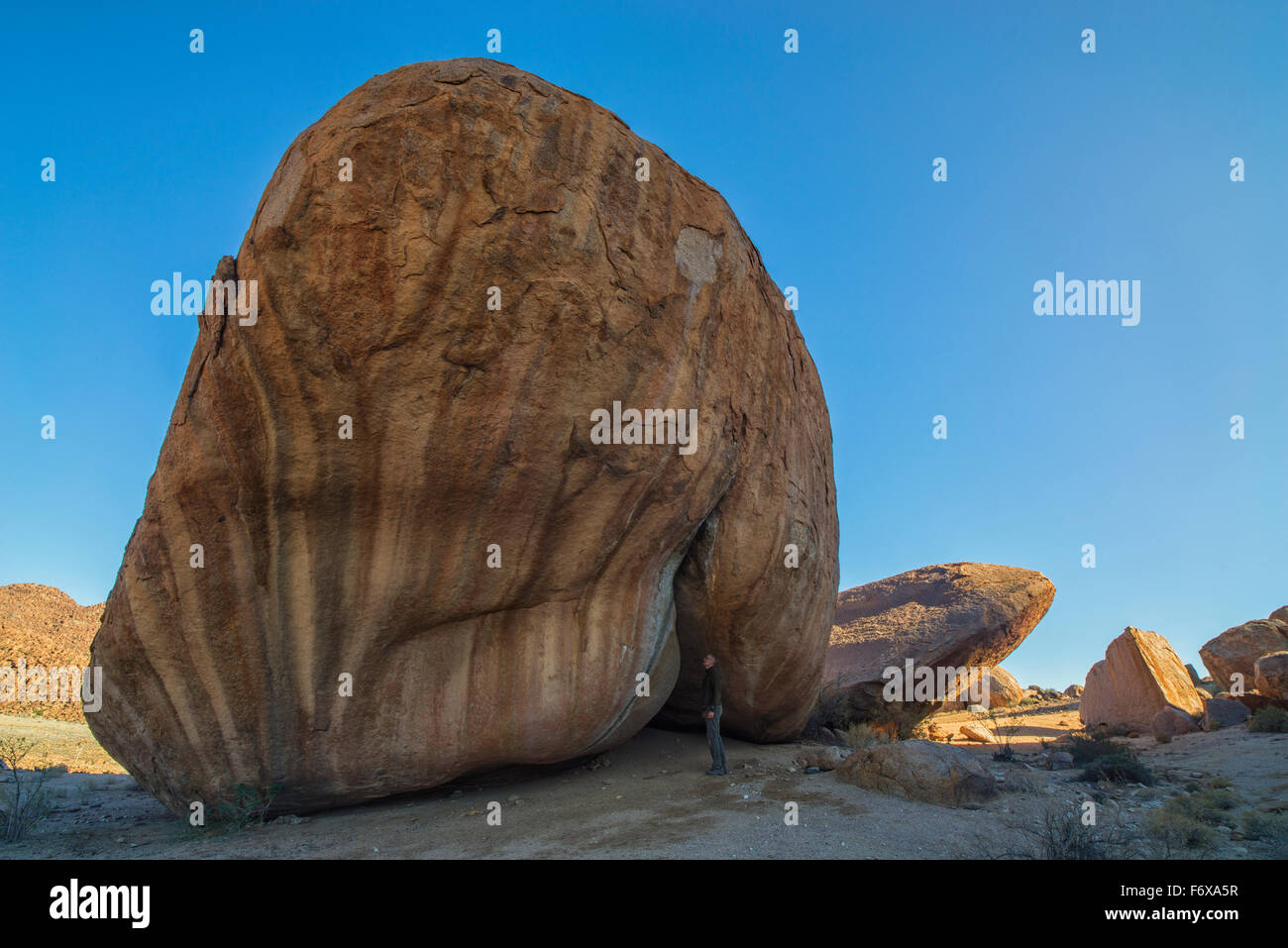 Person standing under a large boulder in Richtersveld National Park ...