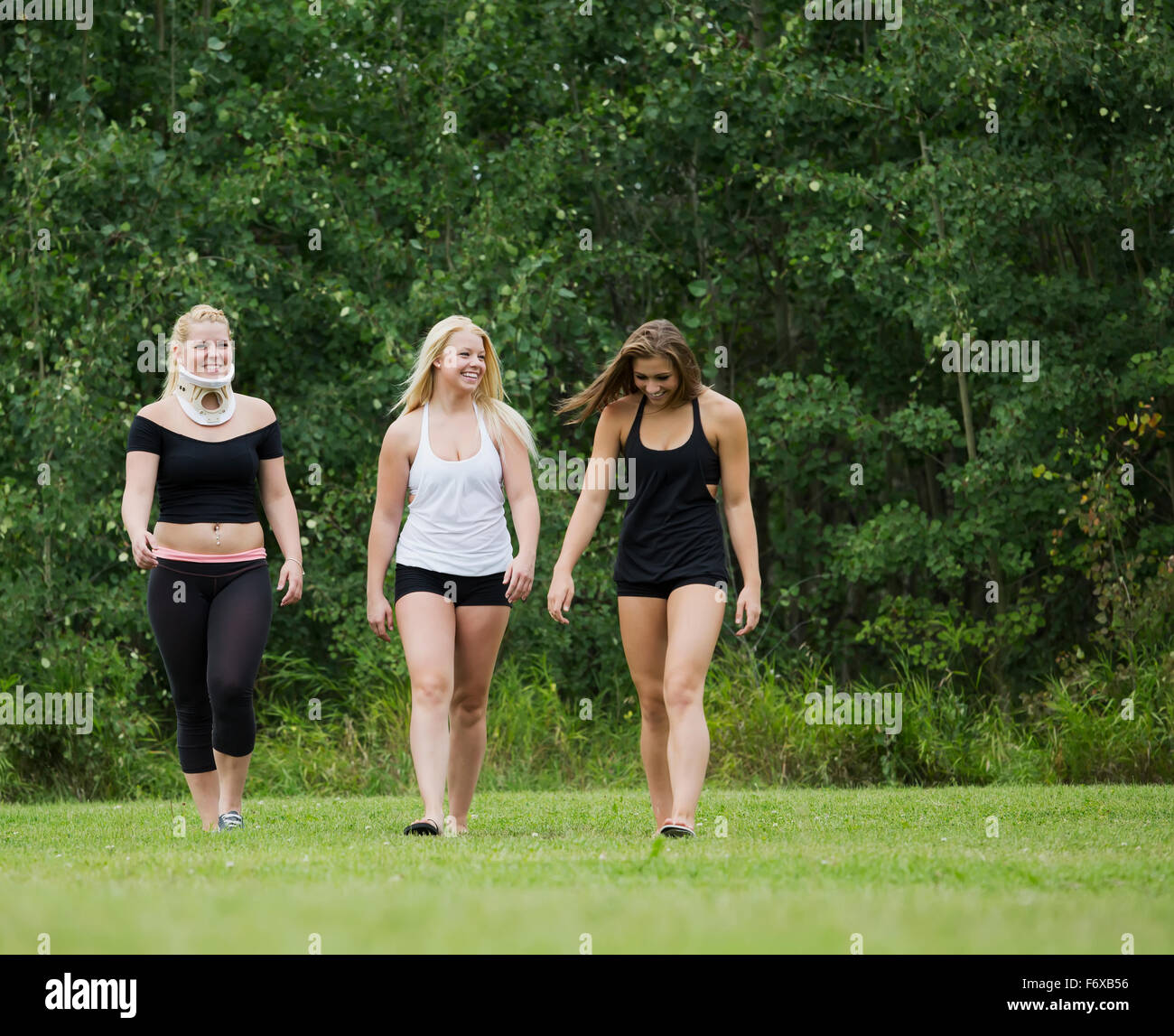 Three young gymnasts walking in a park after practicing their routine ...