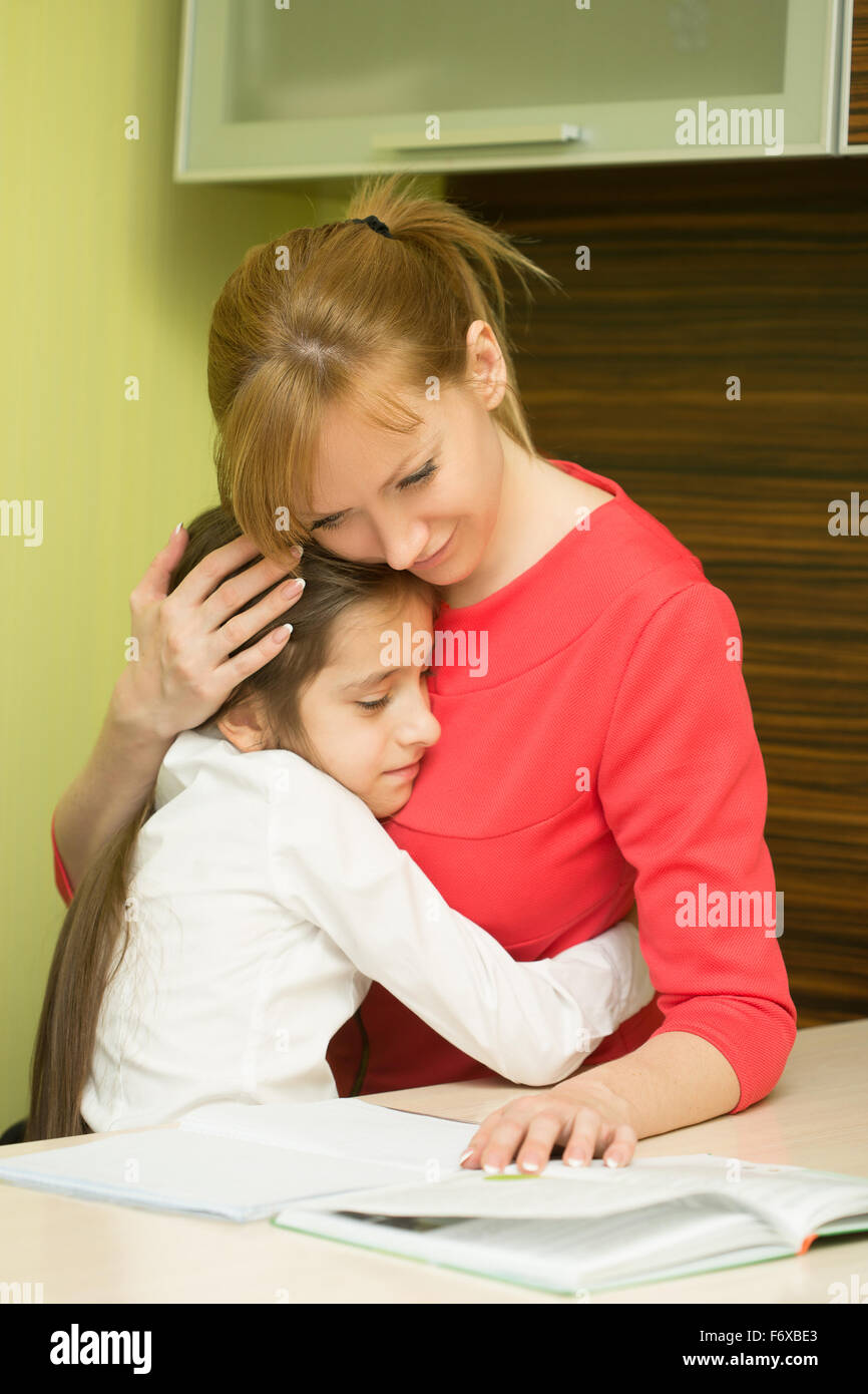 Beautiful school girl doing homework with mother at home Stock Photo ...