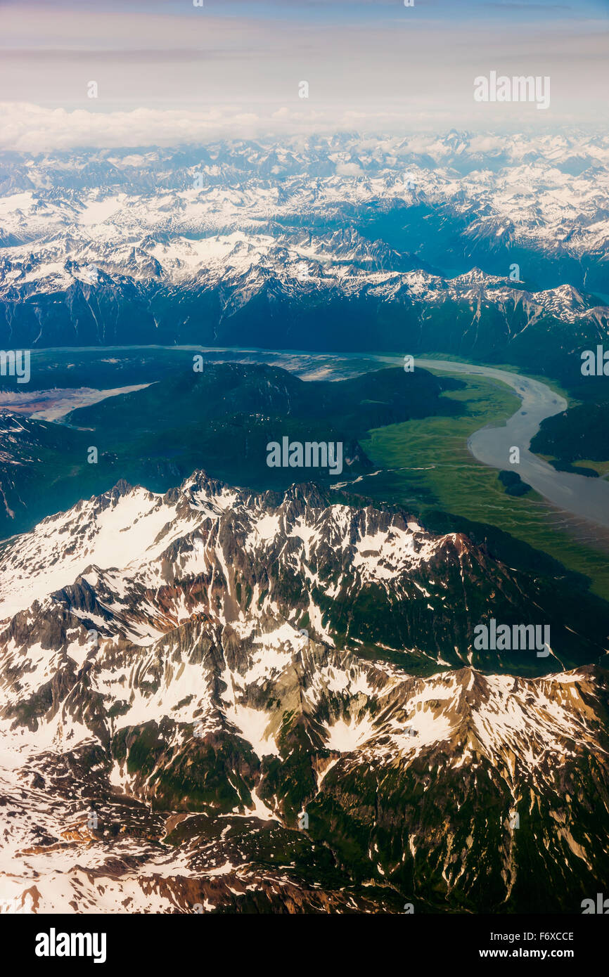 Aerial view of snow-capped peaks surrounding a green river valley ...