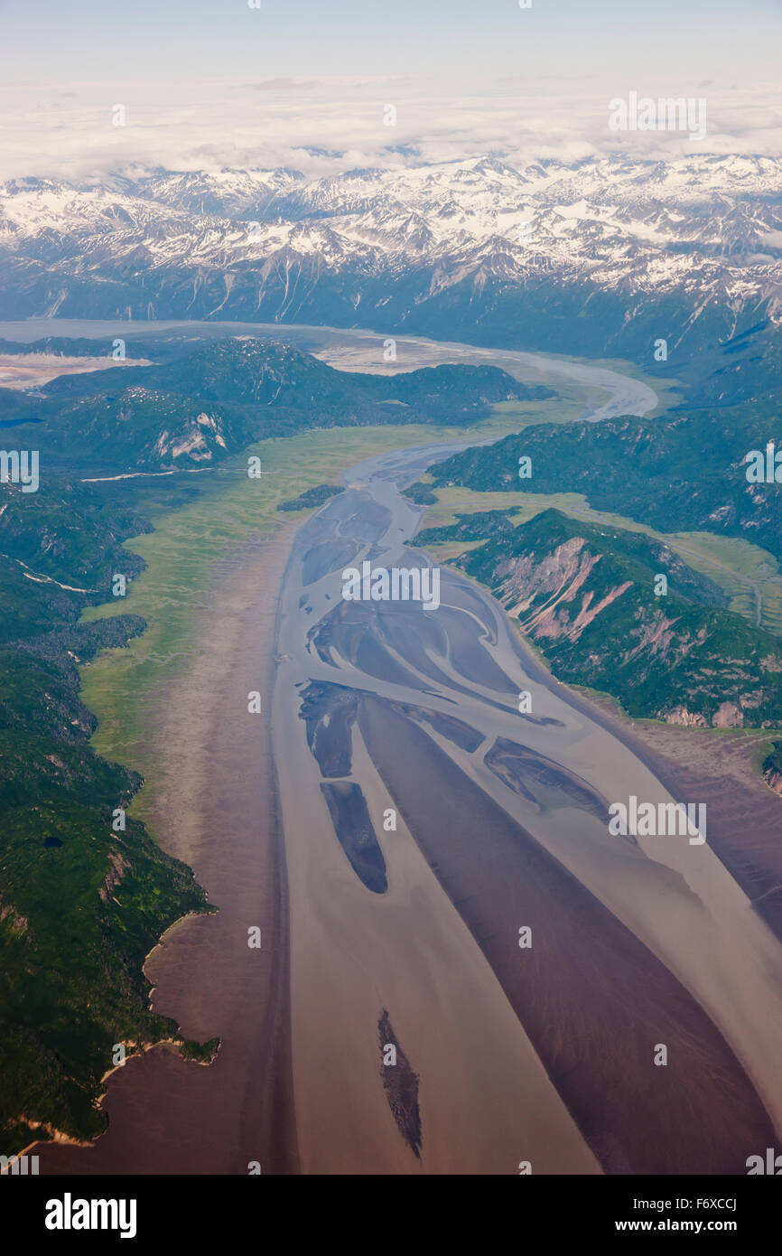 Aerial view of snow-capped peaks surrounding a green river valley ...