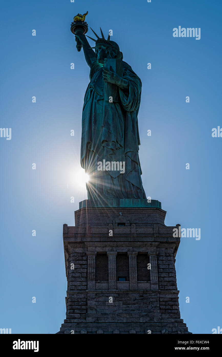 Sun setting behind the Statue of Liberty, Liberty Island; New York City ...