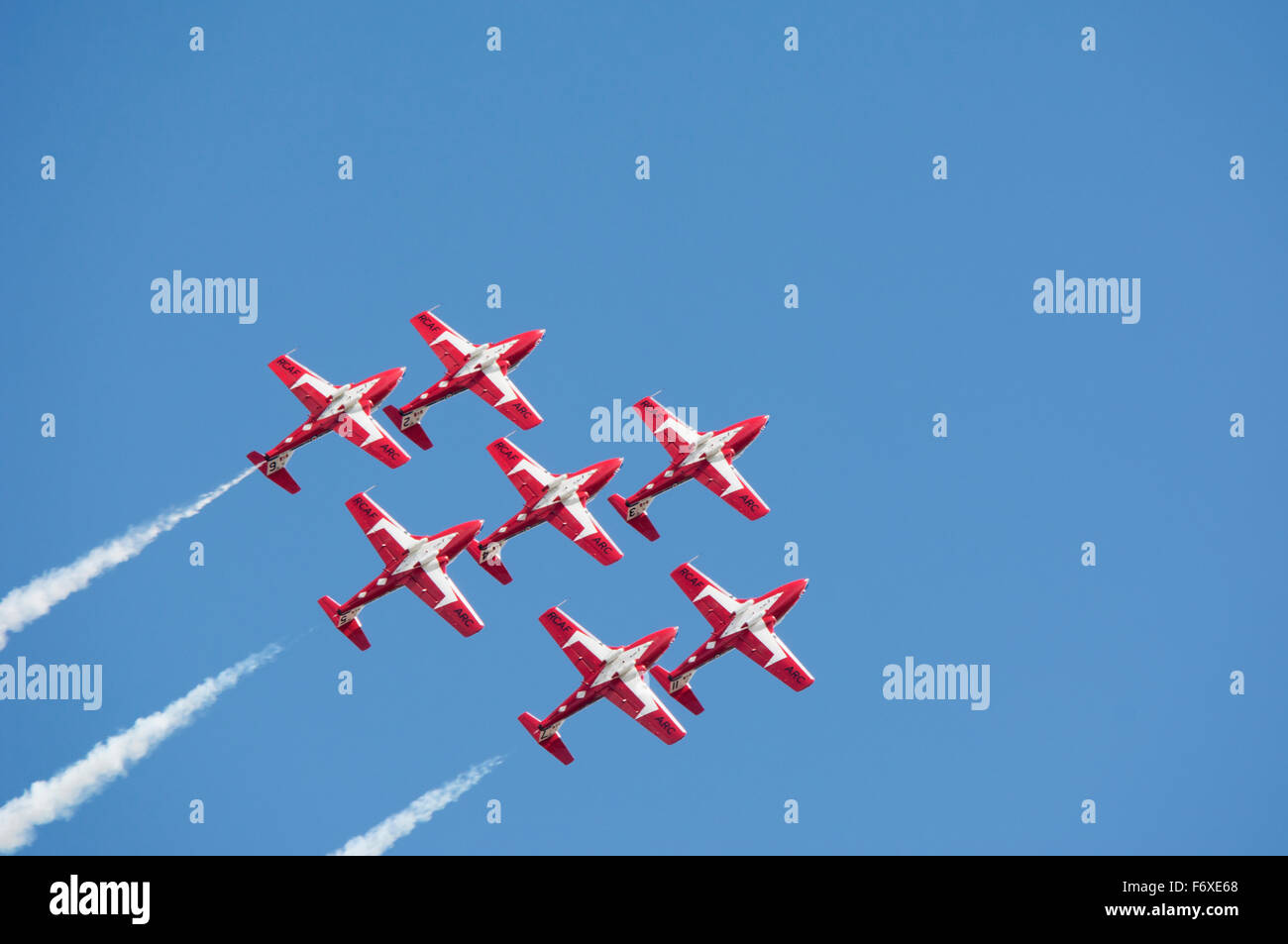 Seven red military aircraft fly in formation against blue sky ...