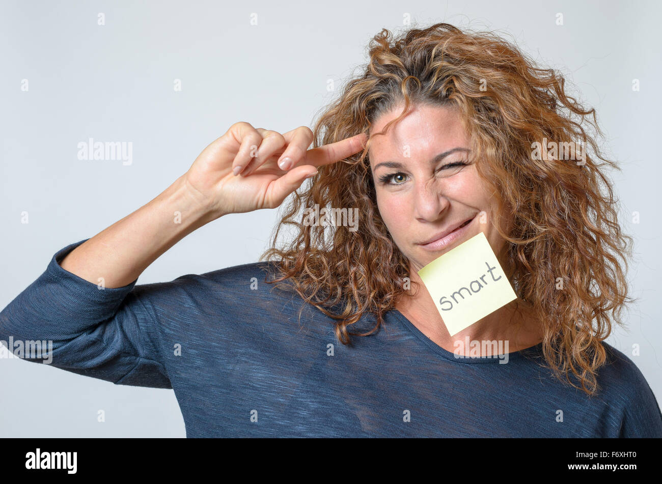 young woman with a sticky note in her face while pointing to her ...