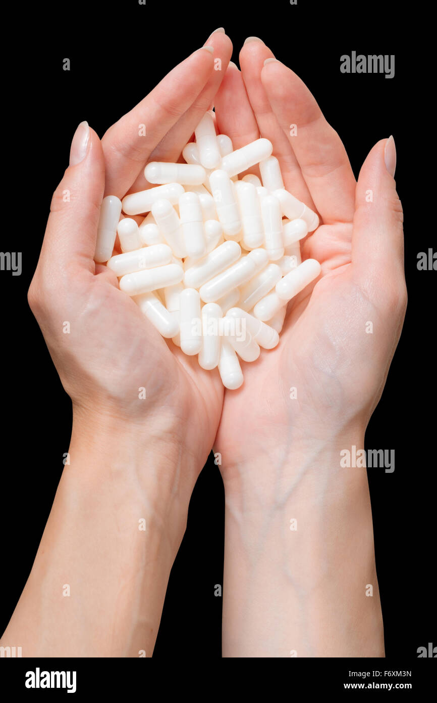 Female hands holding heap of medical capsules isolated on black with ...