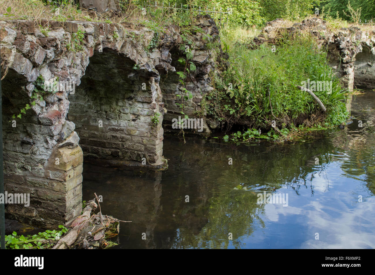 A side angle of an old stone bridge sitting in a river surrounded by ...